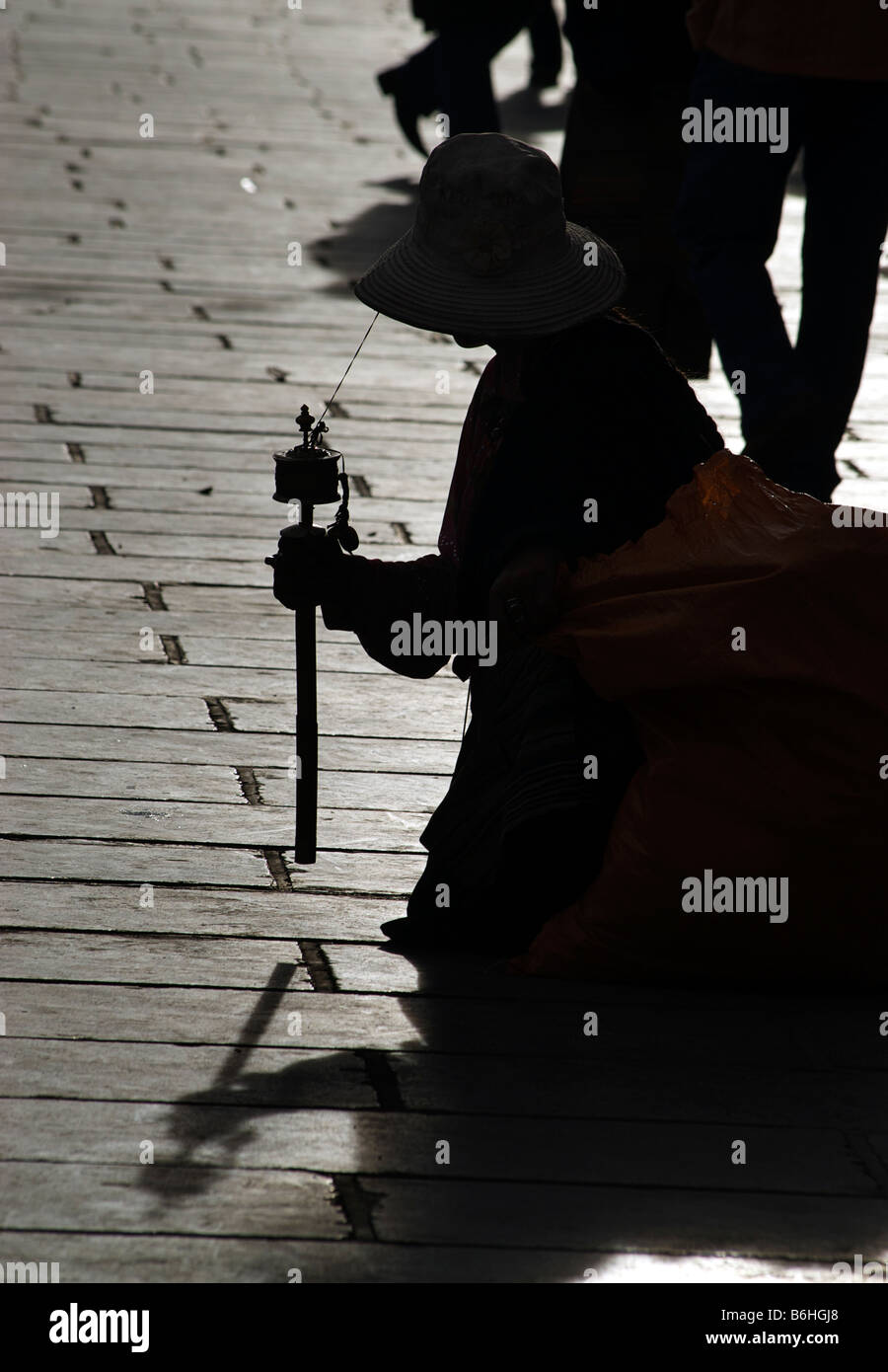 Silhouetted shape of a Tibetan pilgrim in Barkor Square, Lhasa, Tibet ...