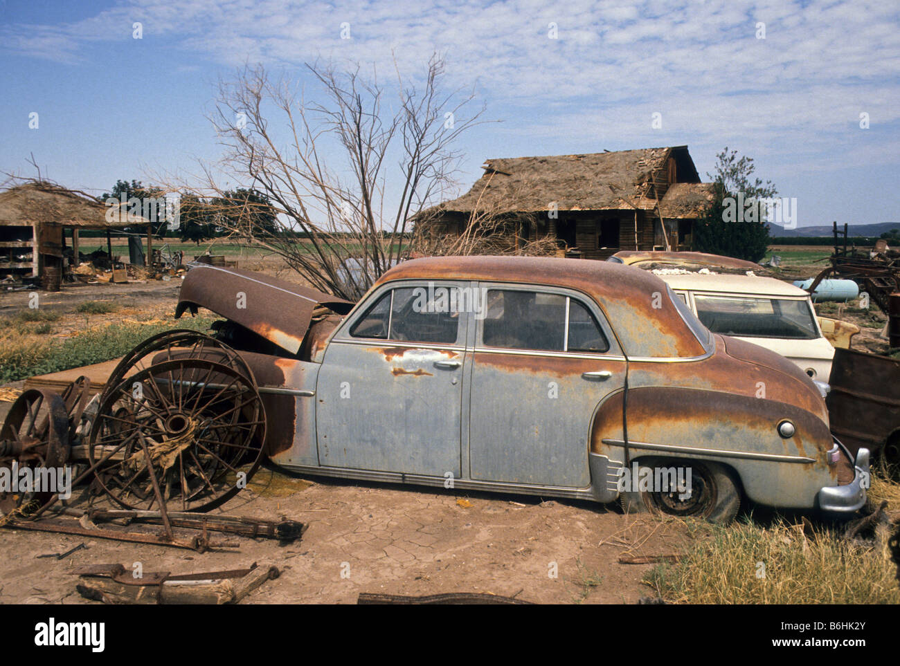 Rusting autos and other old farm machinery rest next to deserted ...
