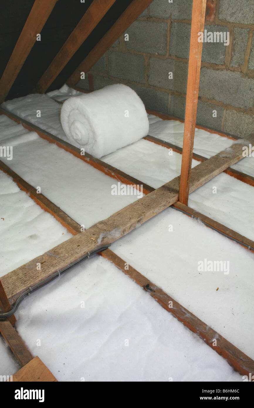 Laying loft insulation in attic roofspace Stock Photo - Alamy