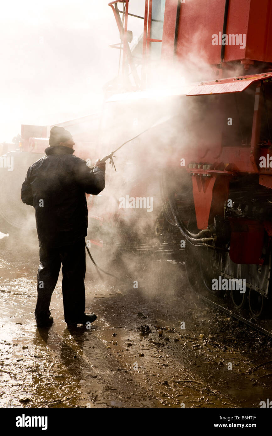 A farmer pressure washing a potato harvester after the potato harvest ...