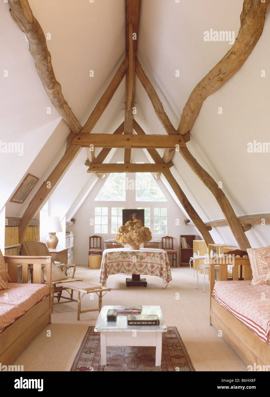 Rough wooden beams on apex ceiling in country living room with pink ...