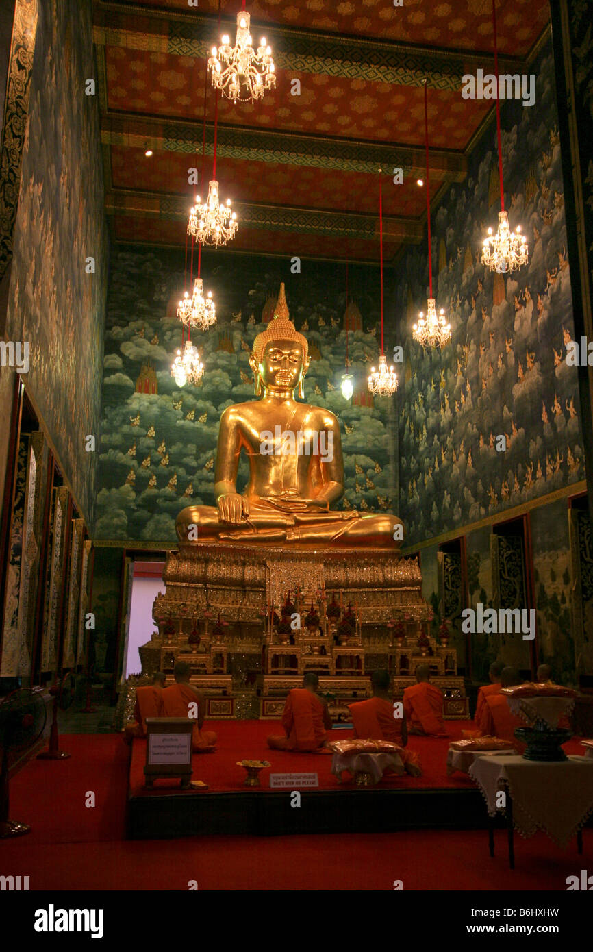 inside wat Rakhang Kositaram tempel, monks praying big golden buddha ...