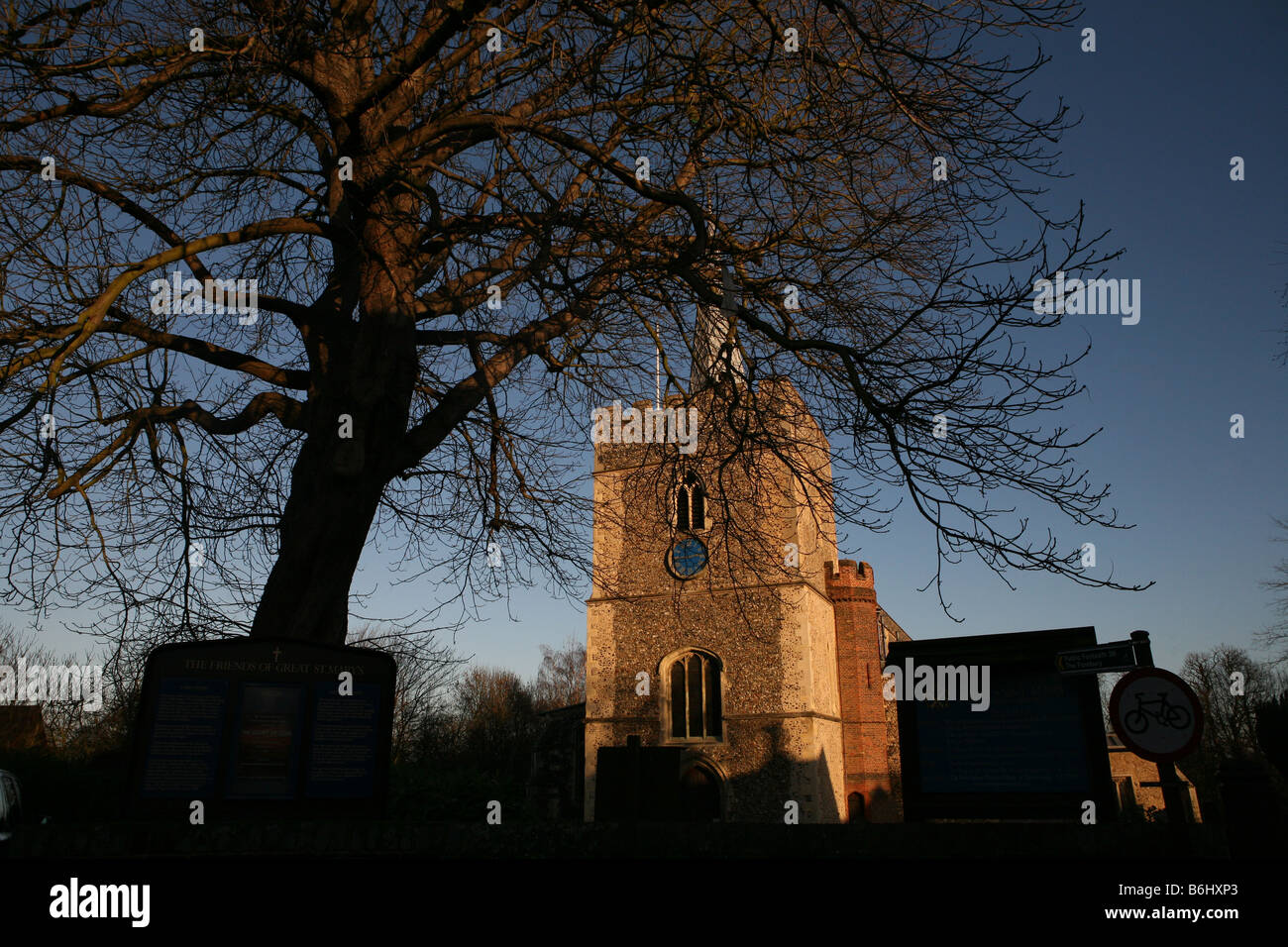 a traditional english church with a cross silhouetted against a deep ...