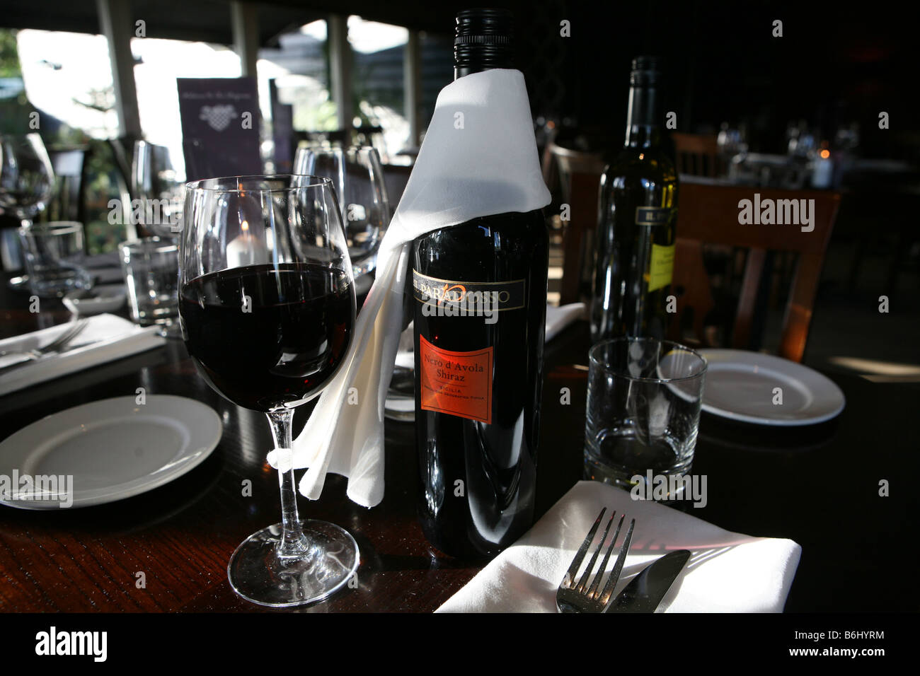 a classy bottle of red wine in a glass and in a bottle on a table in a ...