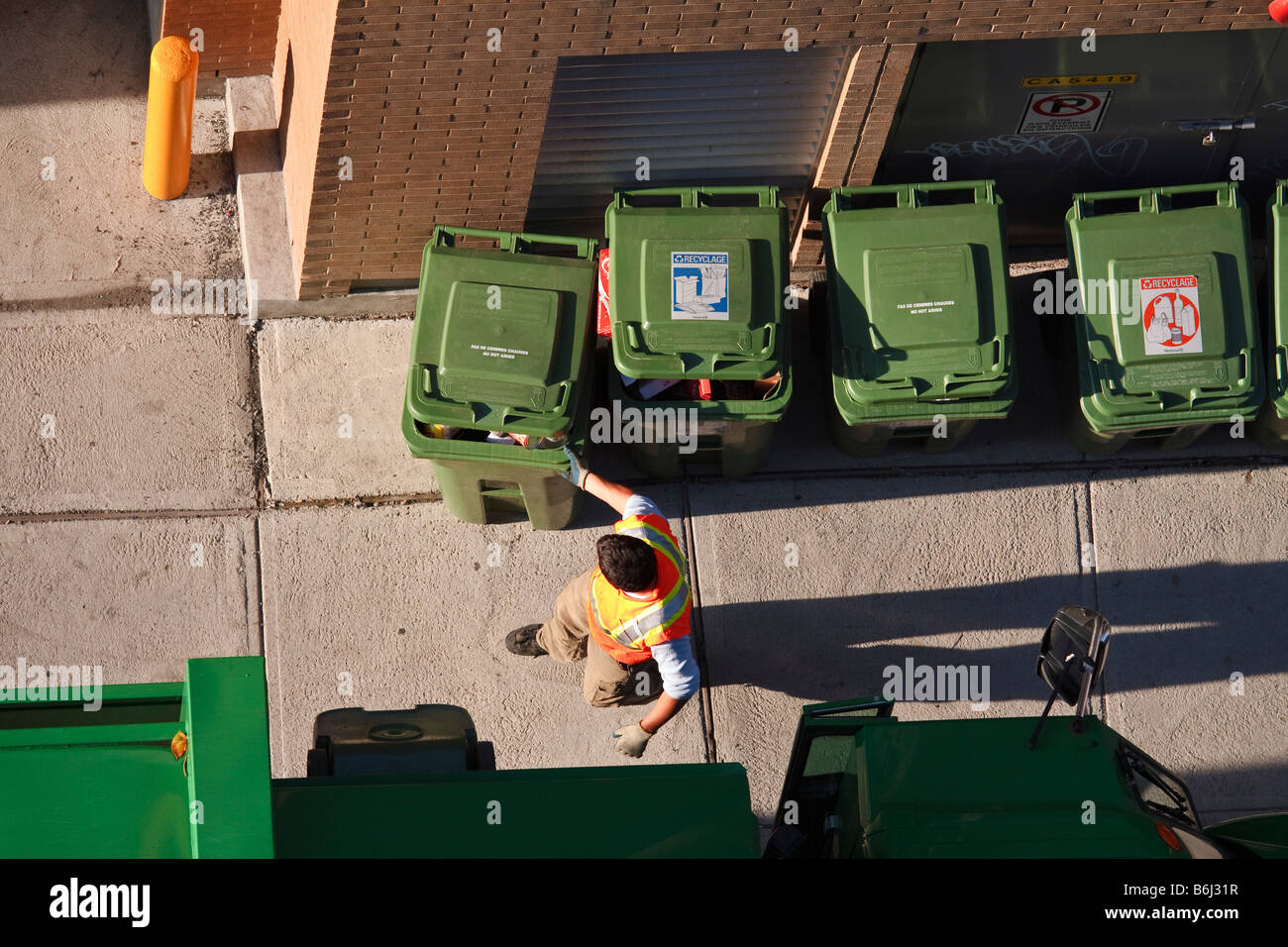 Sanitation worker collecting garbage and loading into garbage truck in ...