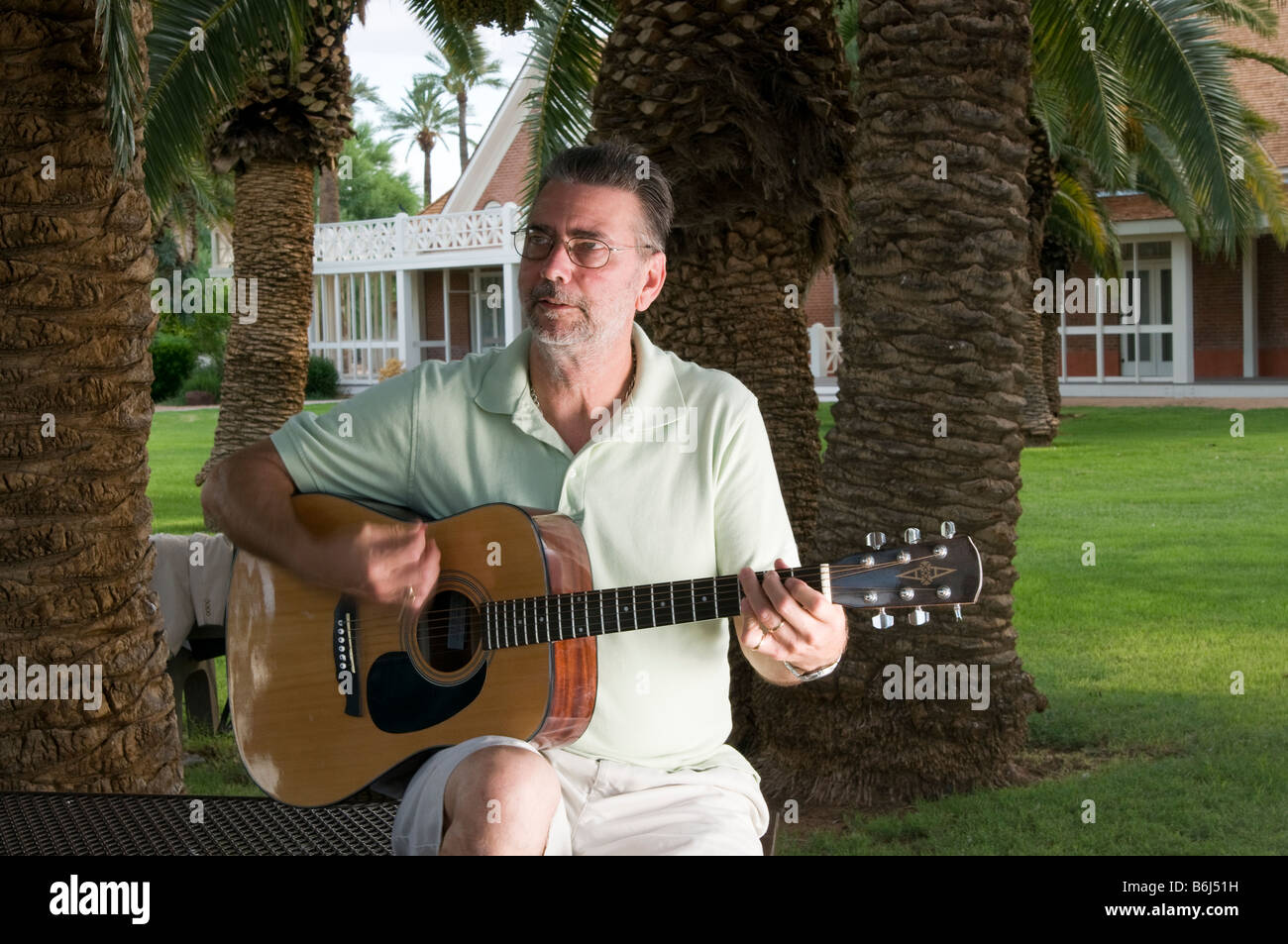 Middle aged man enjoys playing his guitar in the park Stock Photo - Alamy