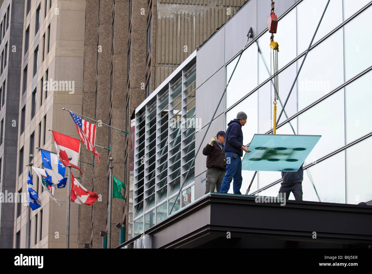 Workmen installing large glass panels in hotel Montreal Quebec Canada ...