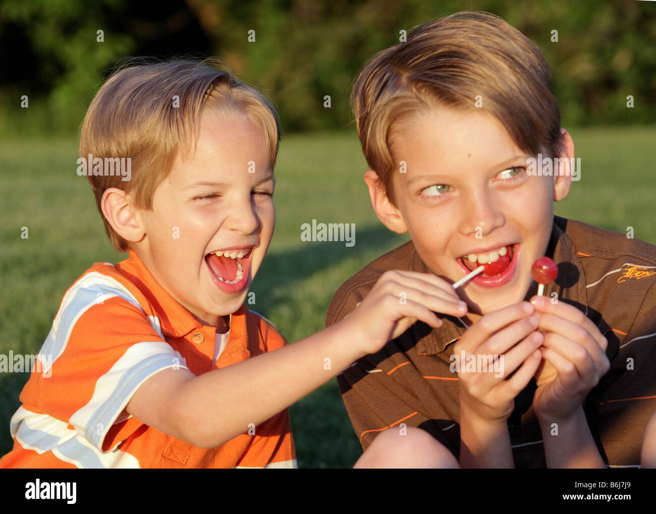 two young boys sharing candy suckers outdoors Stock Photo - Alamy