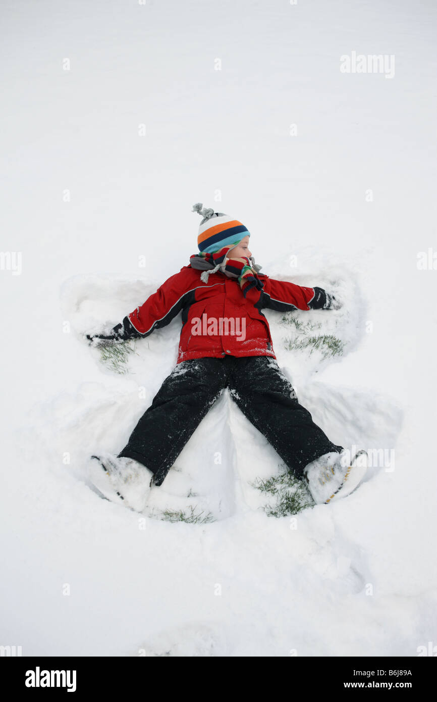 Winter scene with young boy laying in snow making a snow angel Stock ...