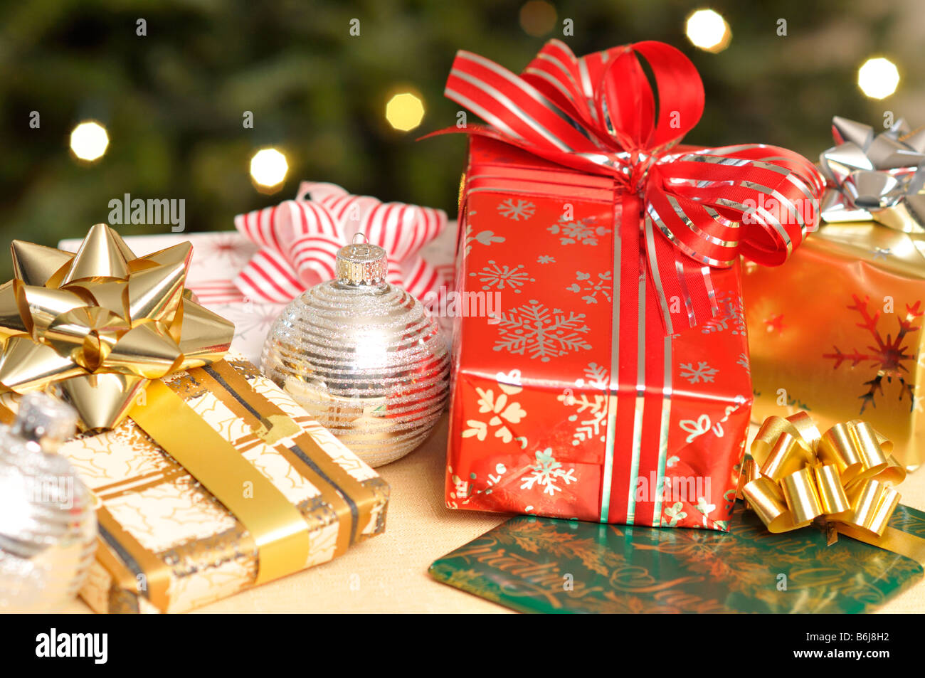 Scene of wrapped Christmas Gifts on festive table with lighted tree in ...