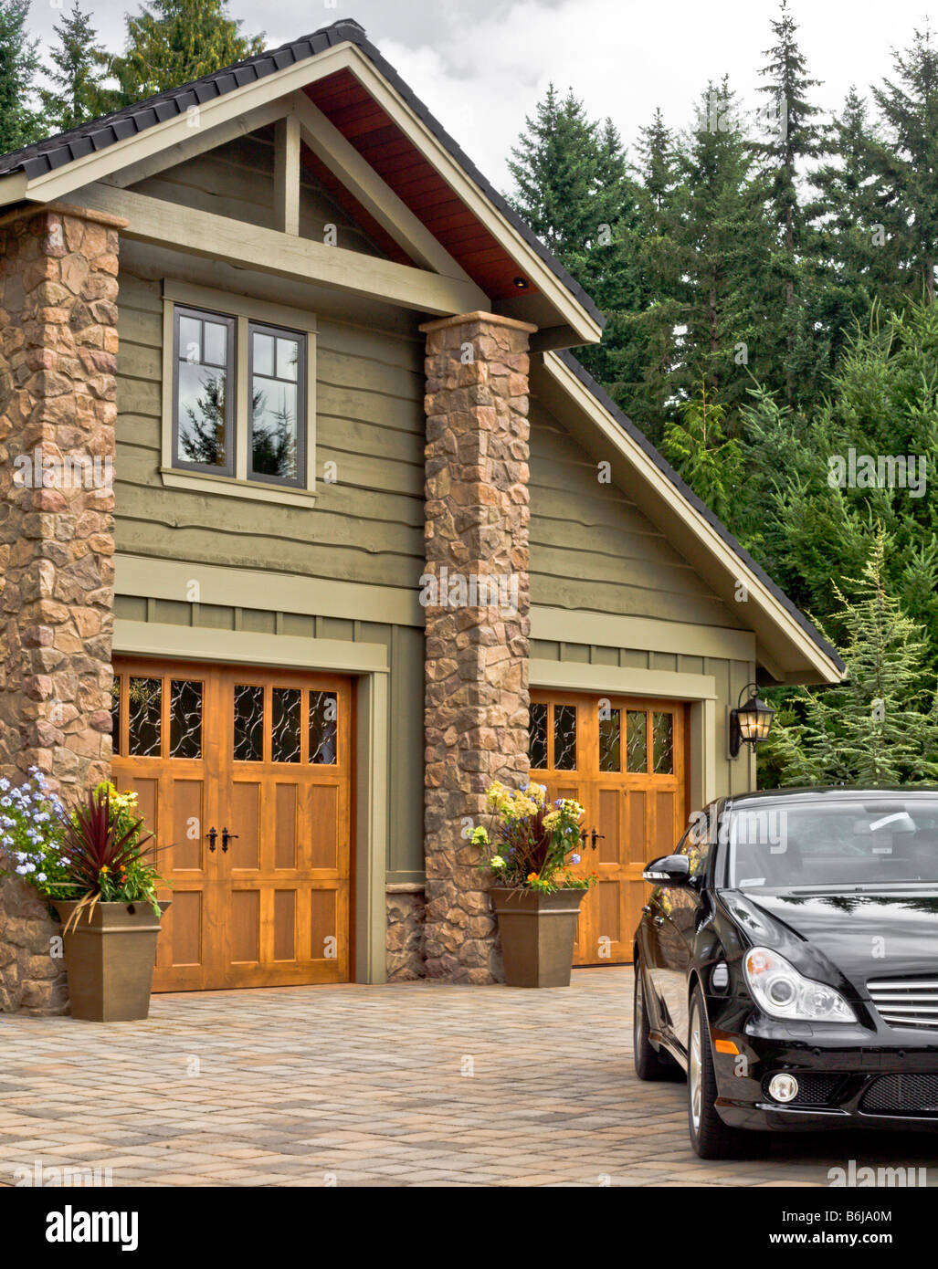Garage with rustic stone pillars, wooden doors, potted plants, and a ...