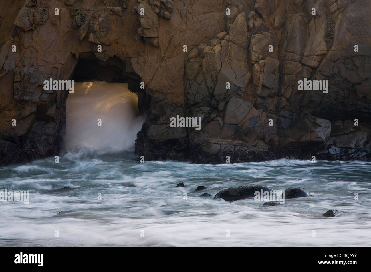 Ocean water burst through an arch in the rock Stock Photo - Alamy