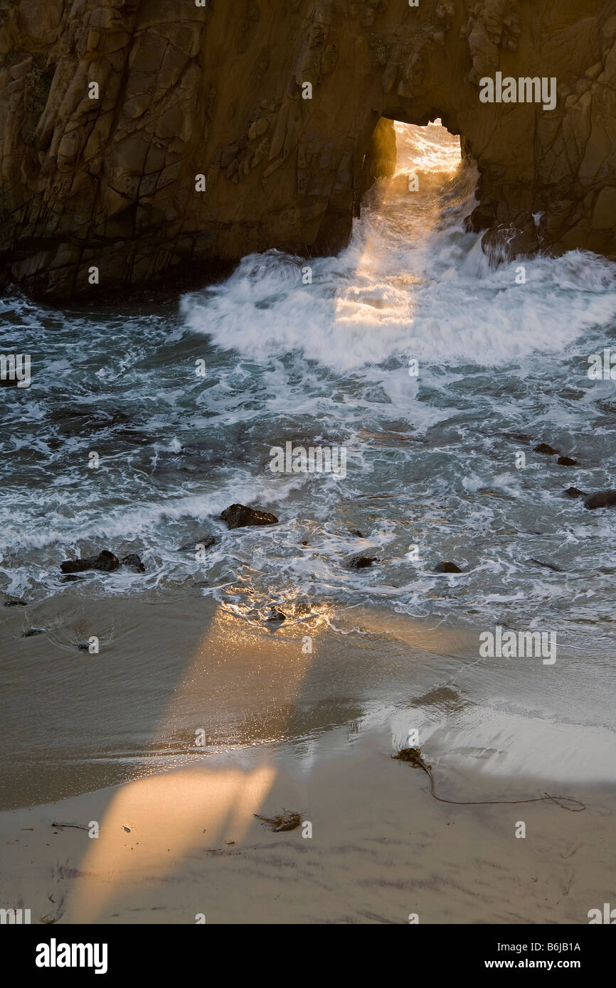 Beam of light shining through arch in ocean rock Stock Photo - Alamy