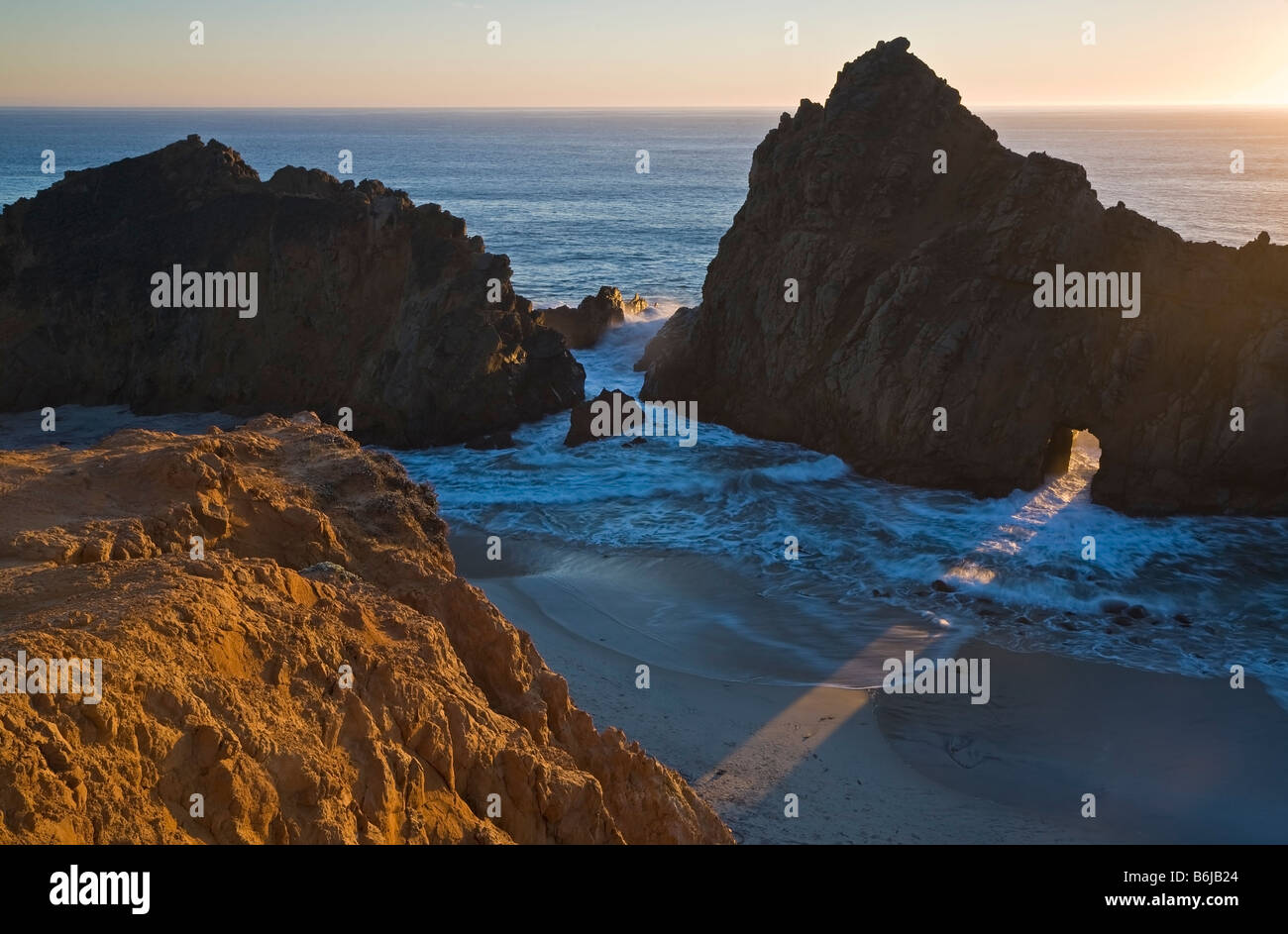 Beam of light shining through arch in ocean rock Stock Photo - Alamy
