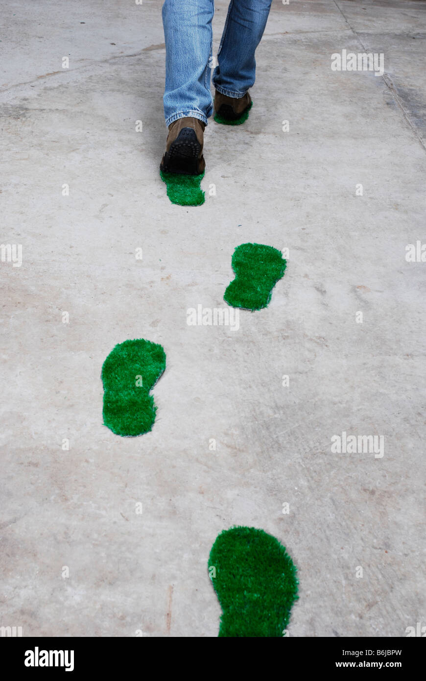 Environmentally friendly man leaving green footprints over a concrete ...