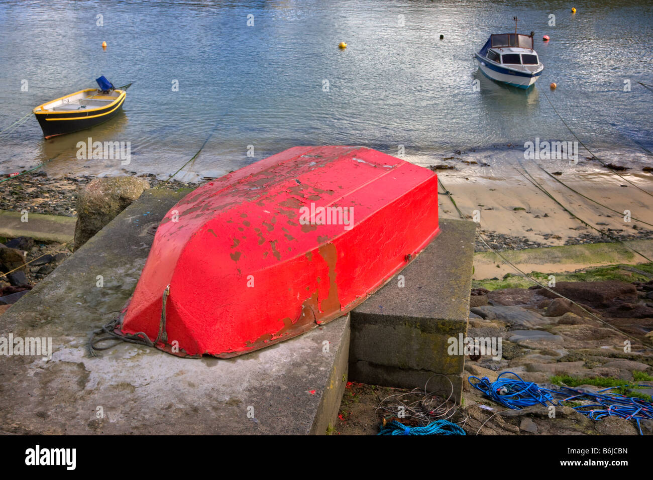 Rusty red dinghy upturned in Mousehole fishing village Cornwall Stock ...