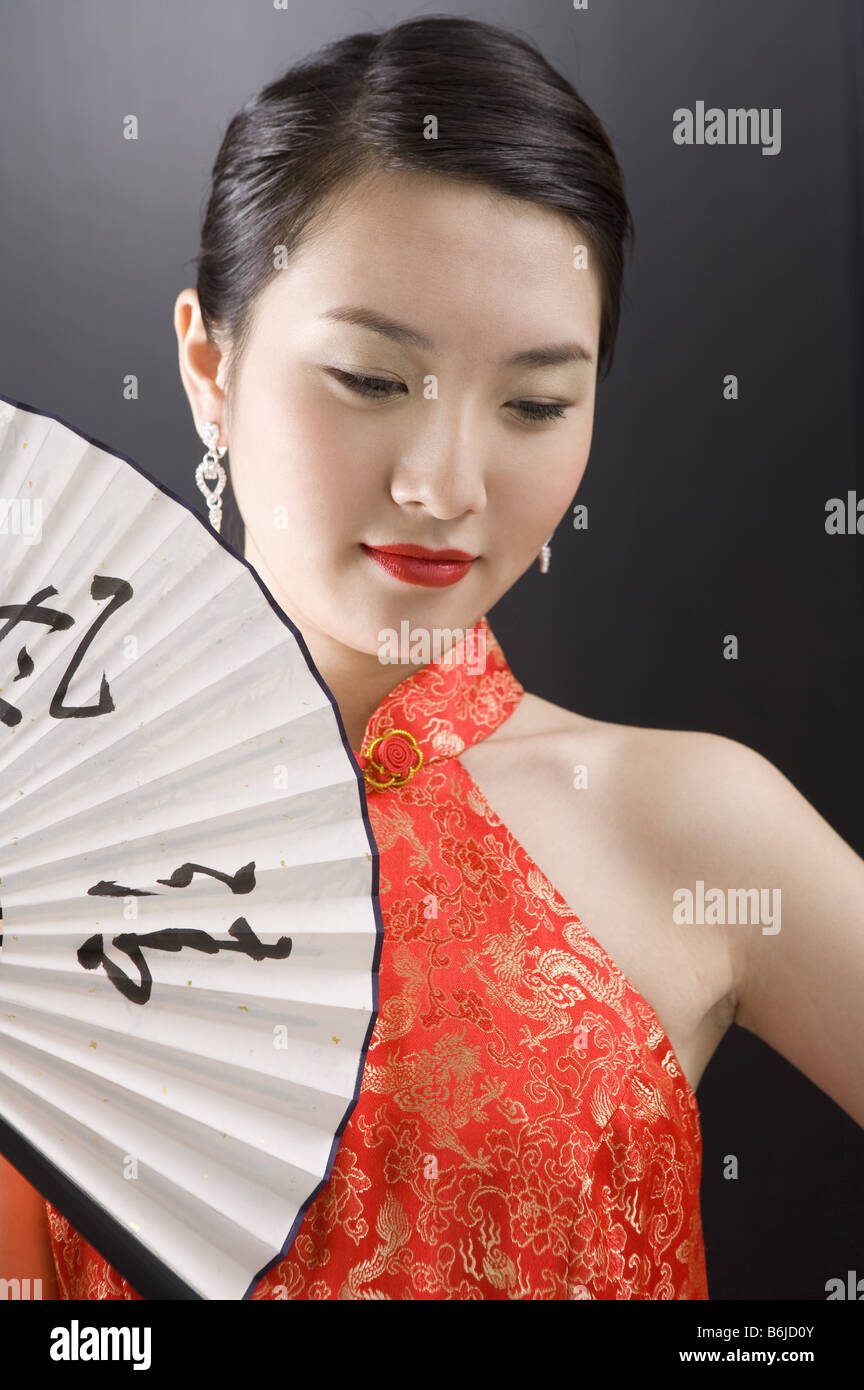 Young woman in cheongsam holding fan Stock Photo - Alamy