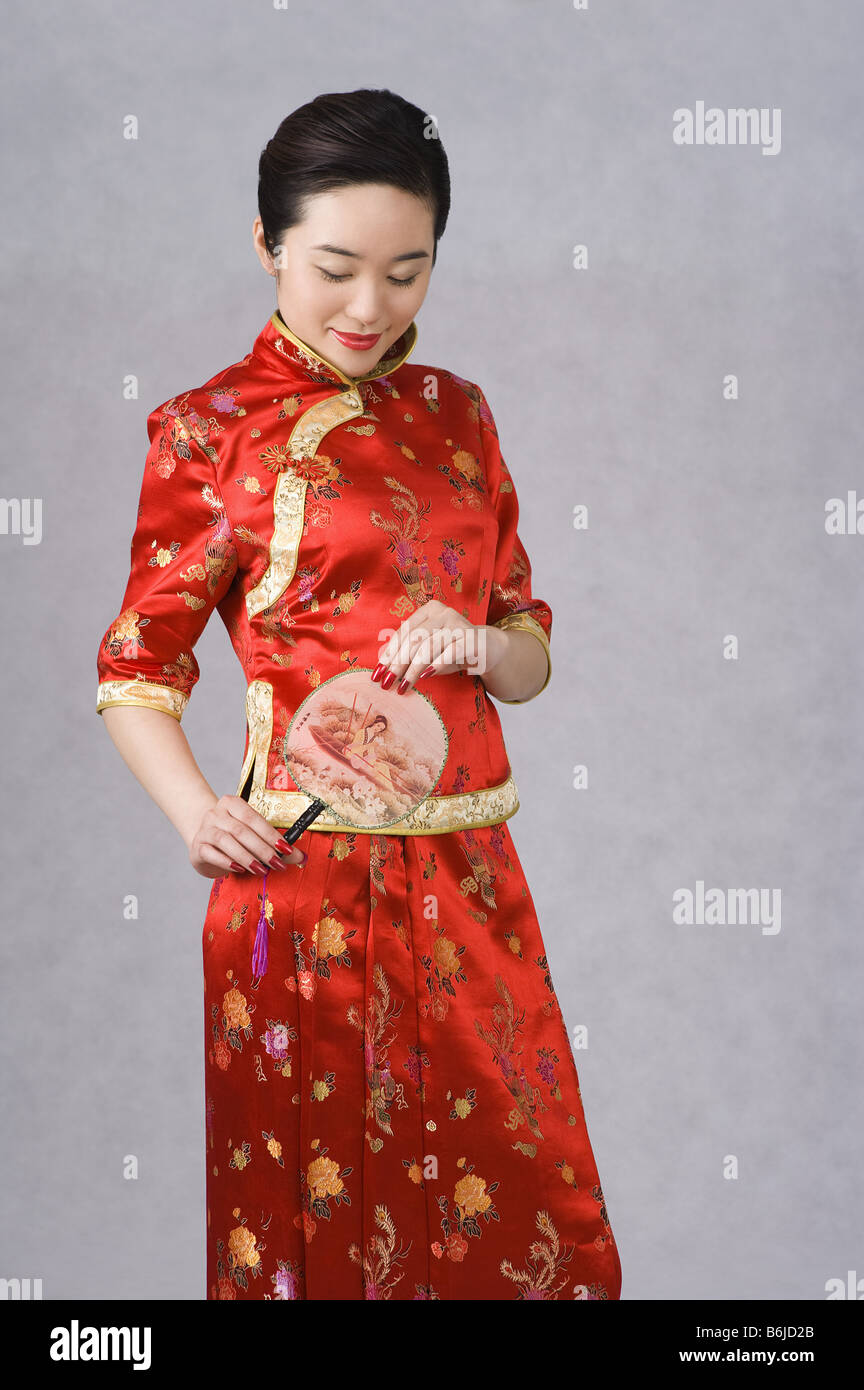 Young woman in cheongsam holding a fan Stock Photo - Alamy