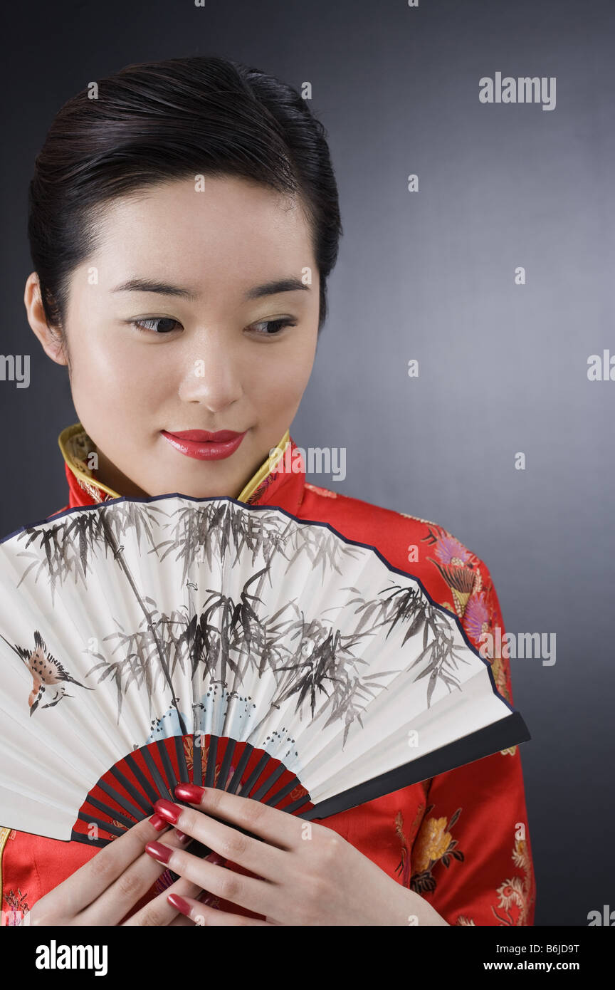 Woman in Cheongsam holding fan Stock Photo - Alamy