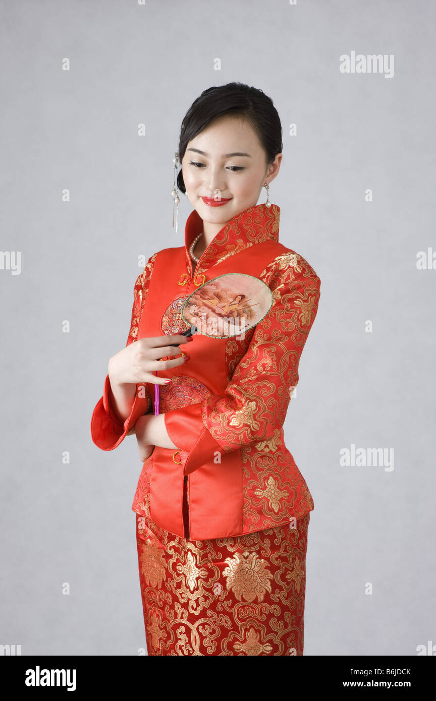 Young woman in cheongsam holding fan Stock Photo - Alamy
