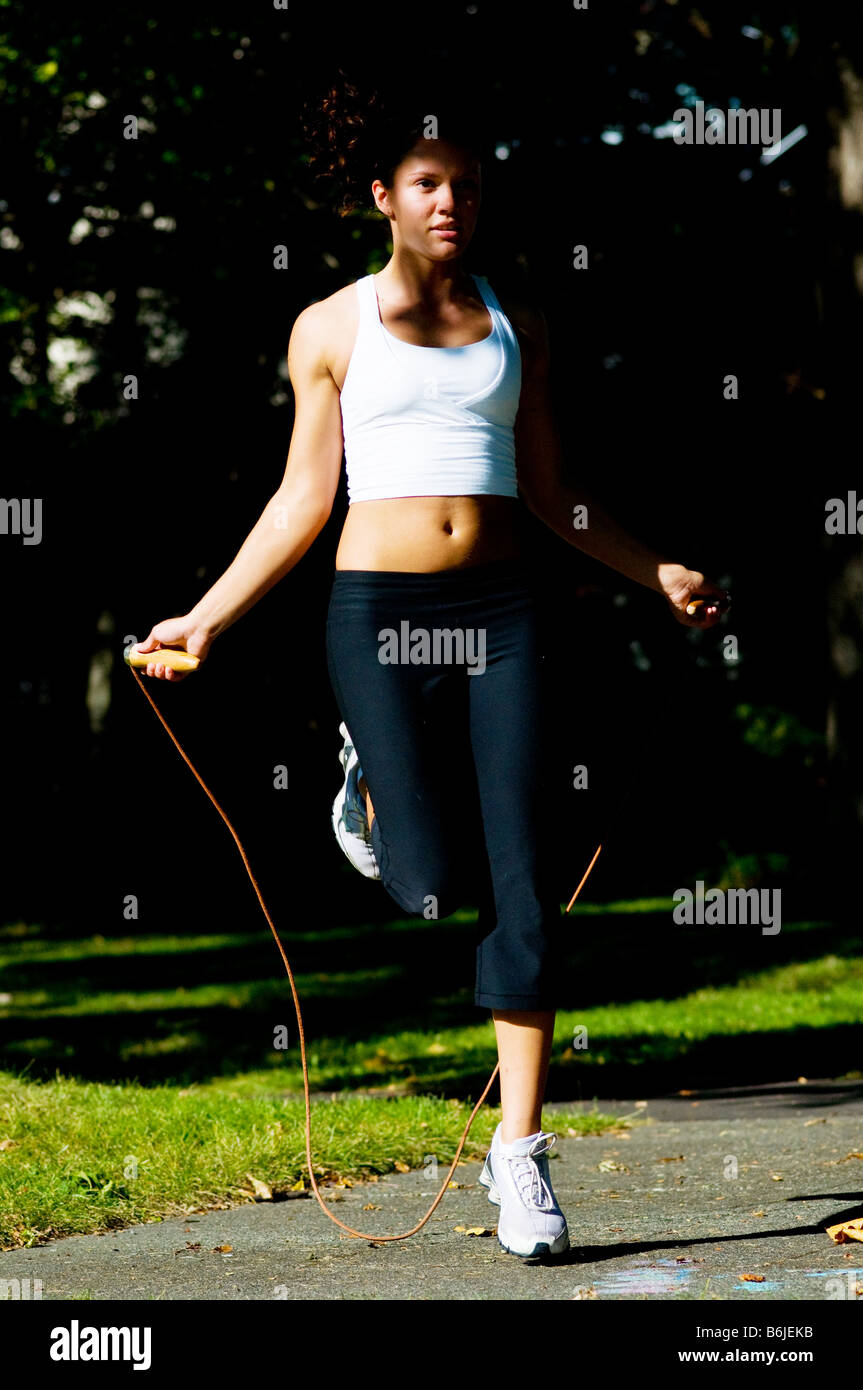 Beautiful young fit woman skipping rope in park Stock Photo - Alamy