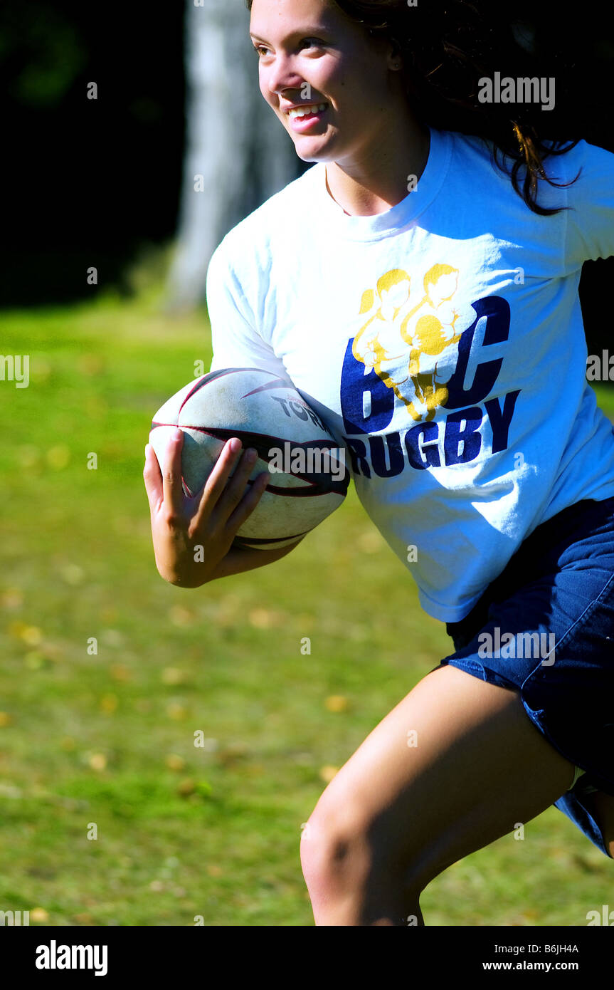 Beautiful young woman running with rugby ball Stock Photo - Alamy