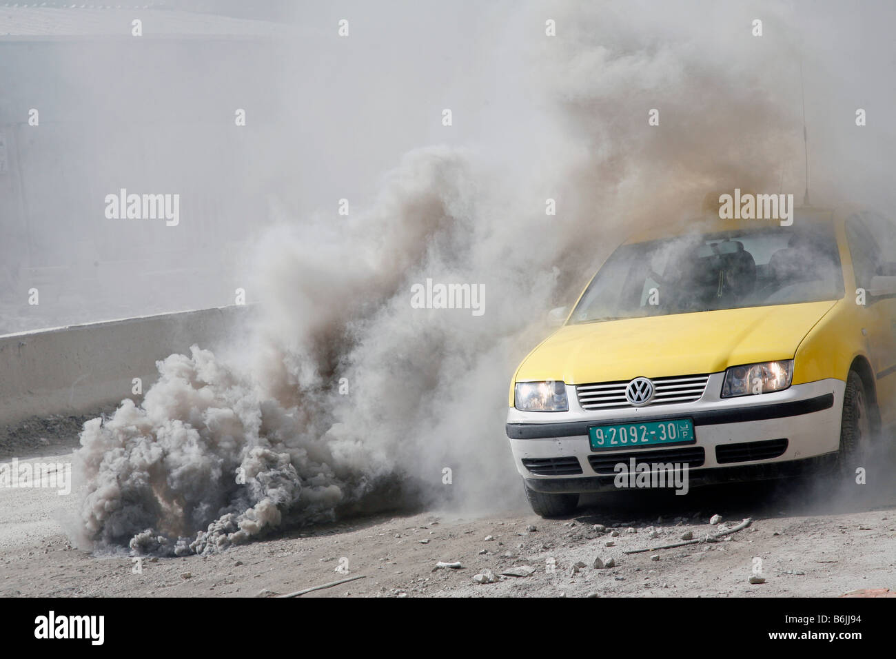 A Palestinian taxi driving through smoke from an Israeli army smoke ...