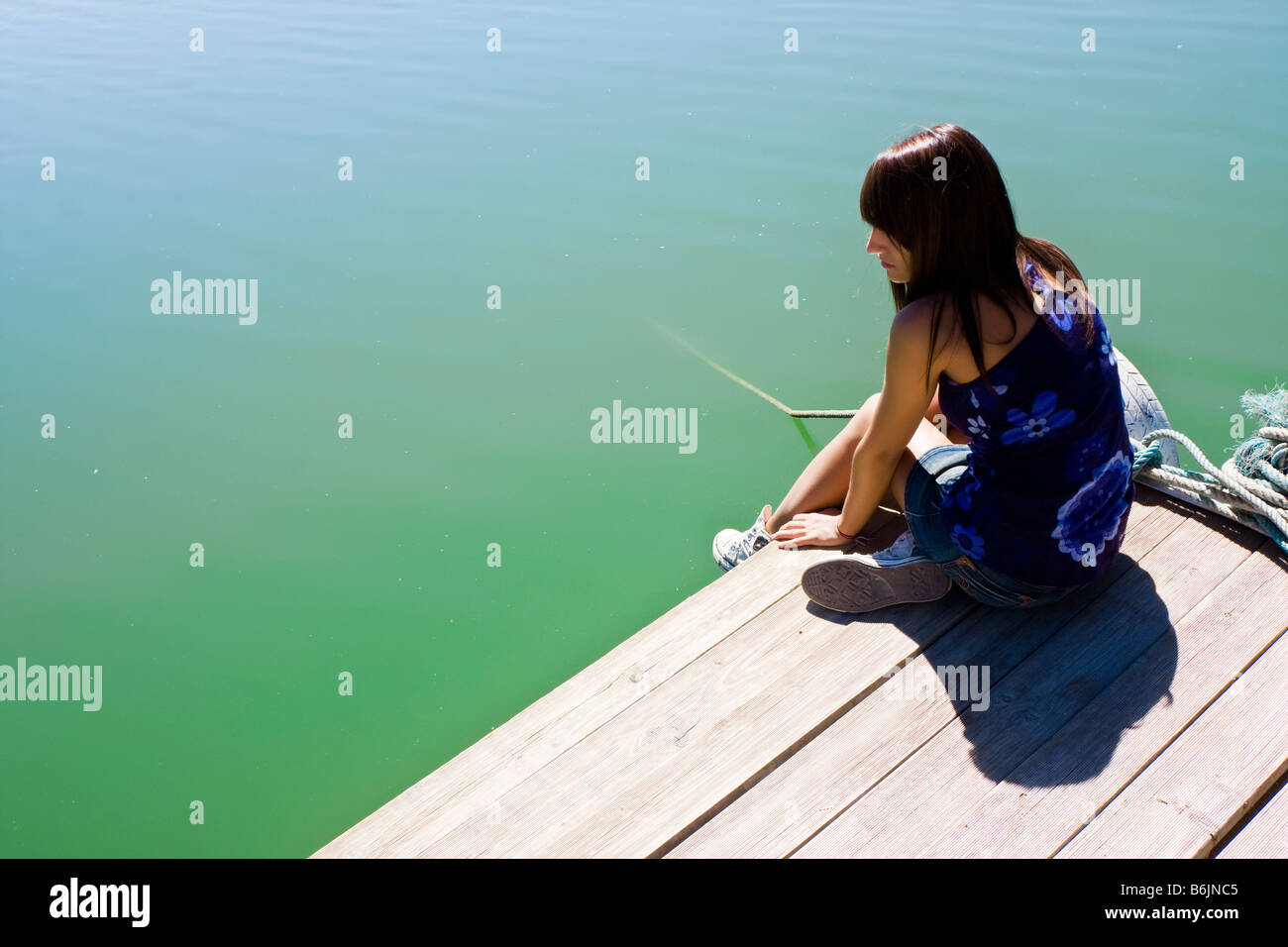Young woman sitting in a pier Stock Photo - Alamy