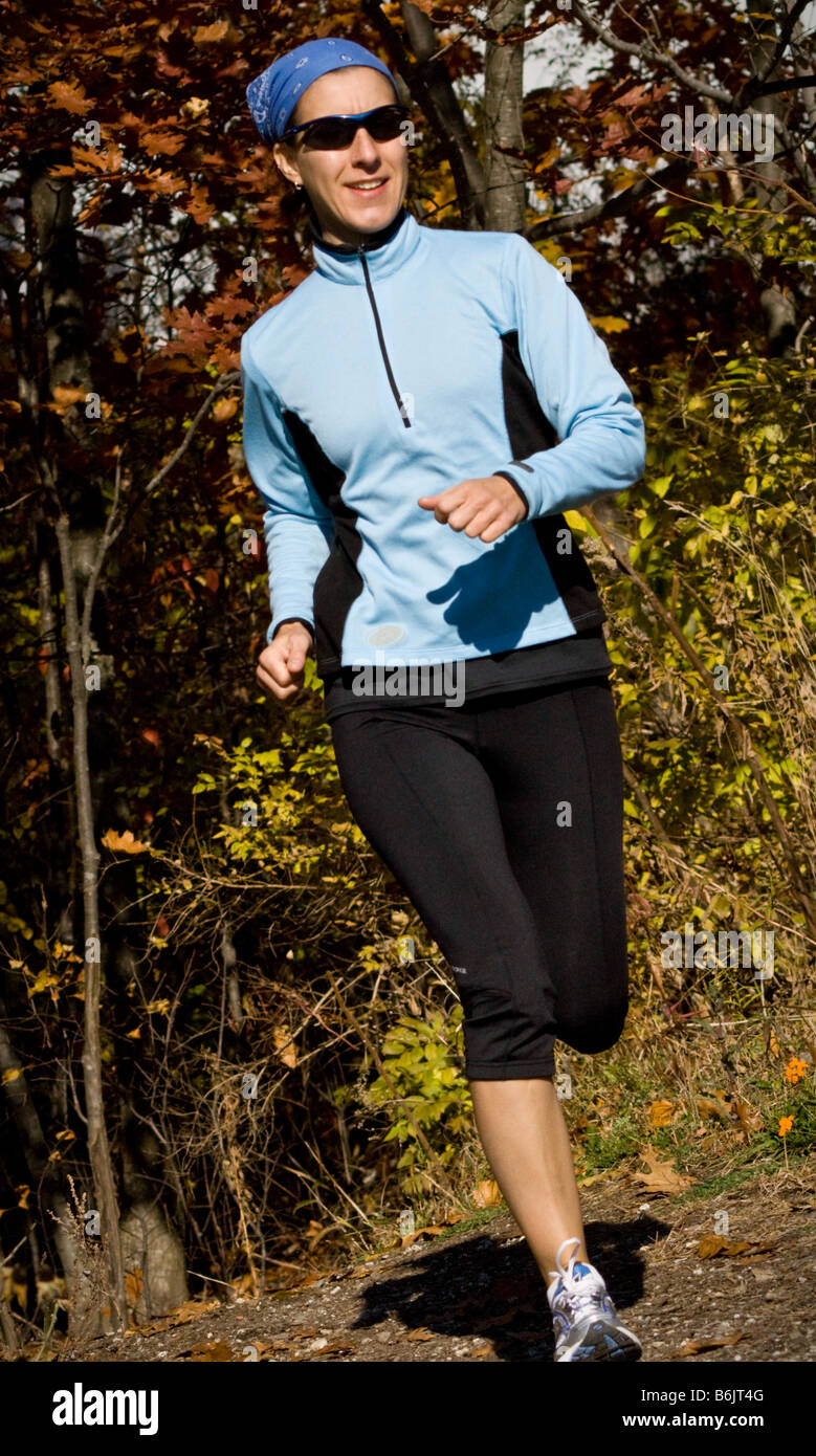 Female trail runner emerges from the forest during her run Stock Photo ...