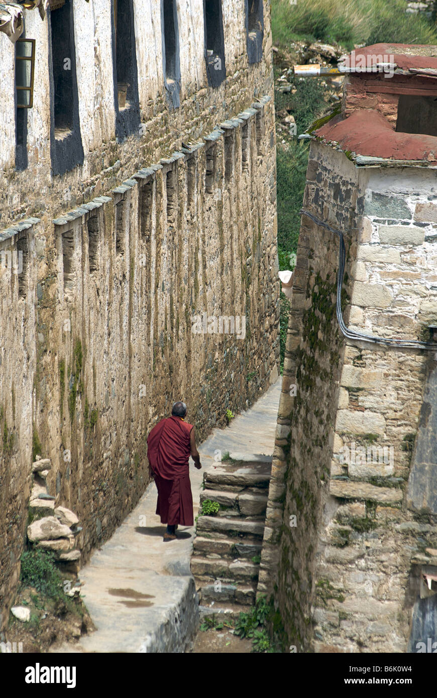 Ganden Monastery. Monk walking along narrow path between monastery ...