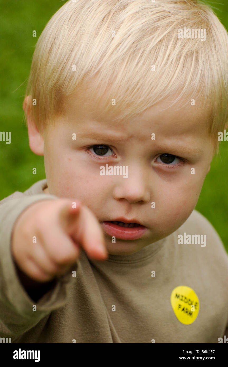 young boy pointing looking straight into camera with puzzled ...