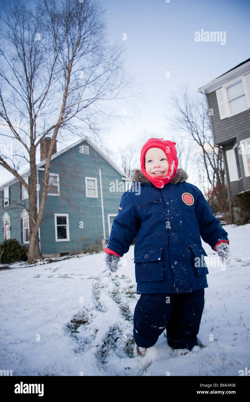 Happy boy walking through snow outside in winter clothing Stock Photo ...