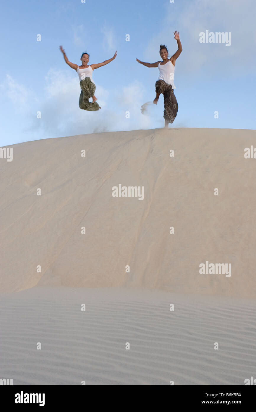 Two women jumping above sand dune Stock Photo - Alamy