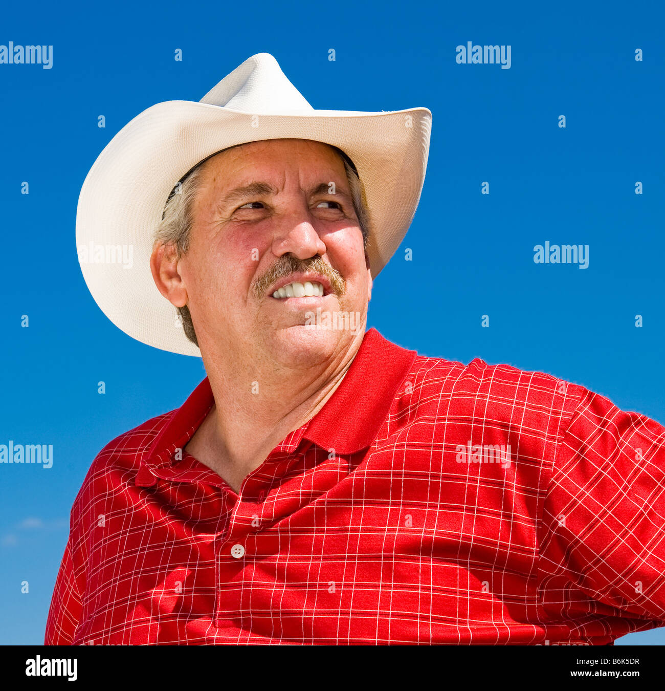 Handsome mature cowboy looks off in the distance with pride and ...