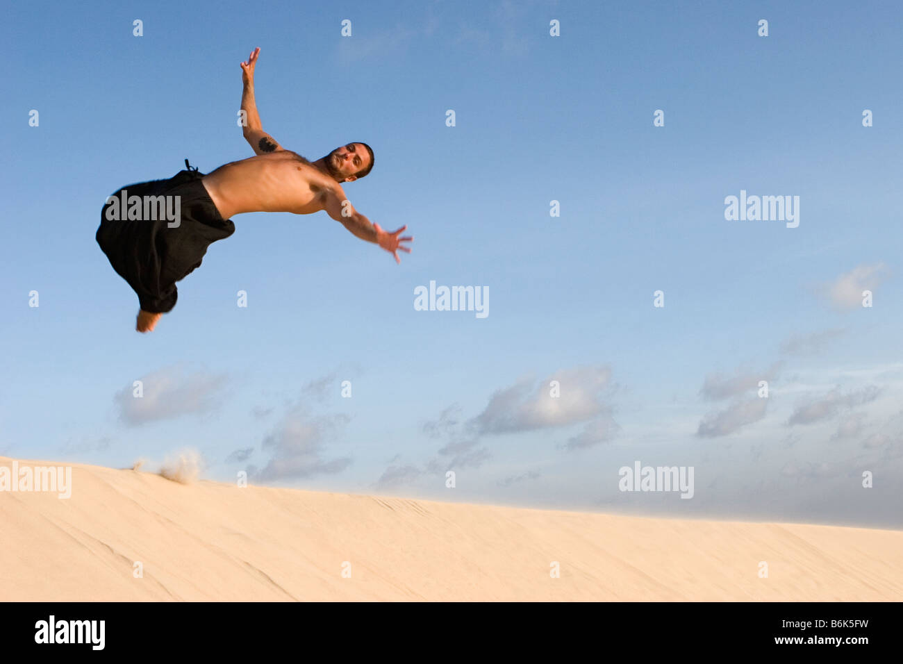 Man jumping above sand dune Stock Photo - Alamy