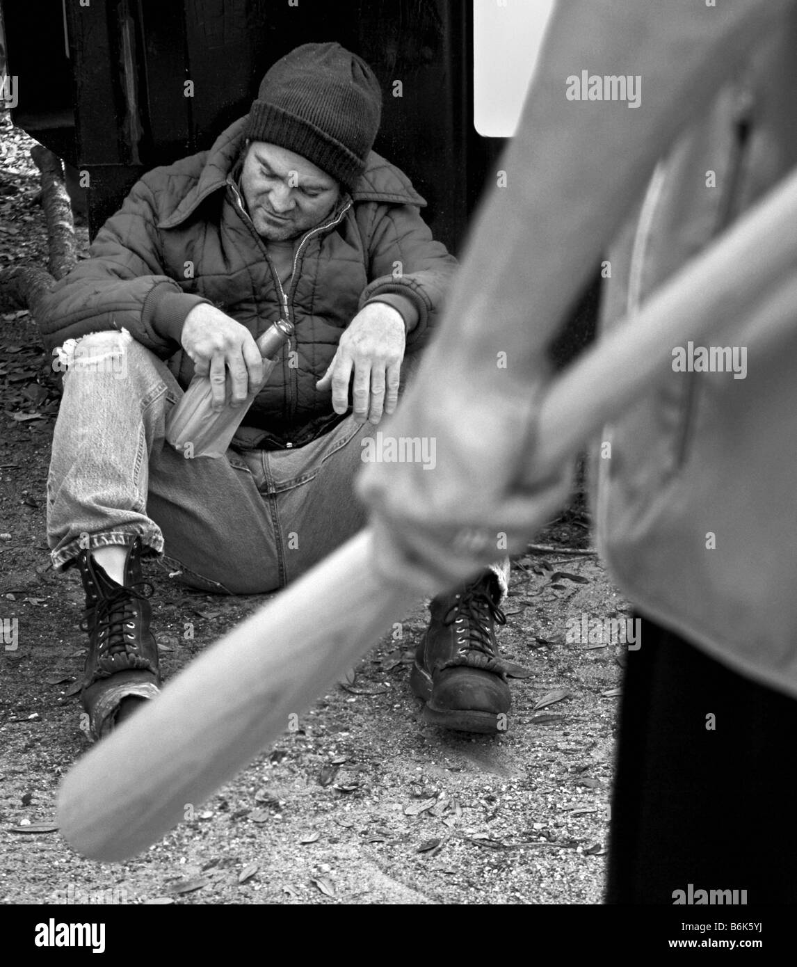 A photo of a homeless man sitting against a dumpster with a teen ...