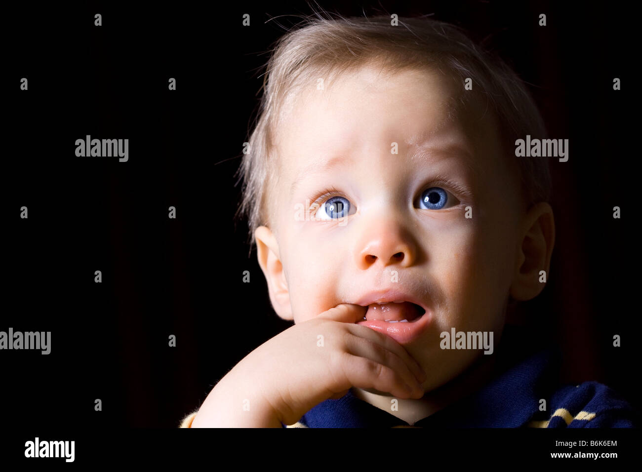 Teething young boy portrait with black background Stock Photo - Alamy