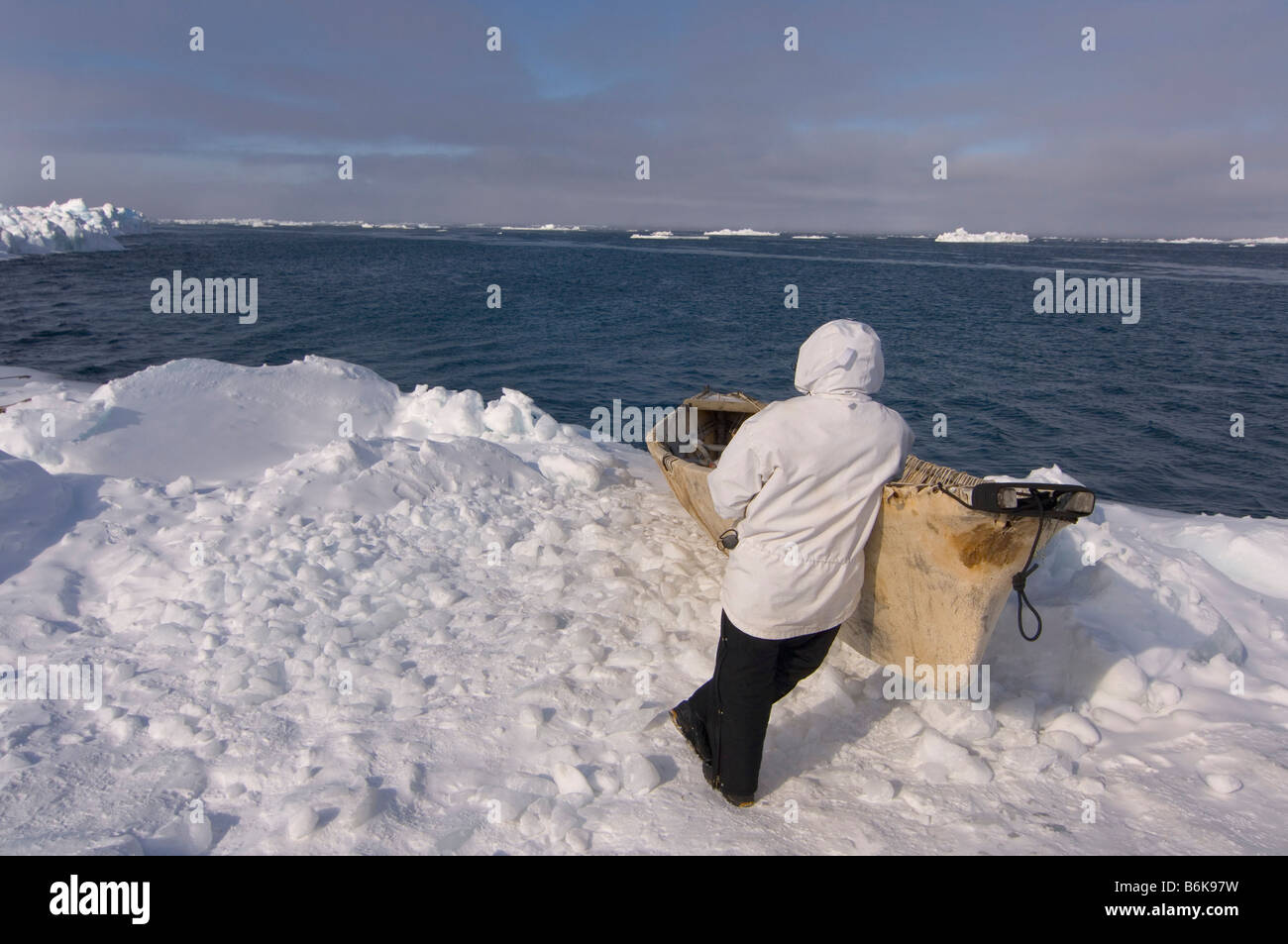 Inupiaq whaler with a seal skin boat or umiak uses a scope to look for ...