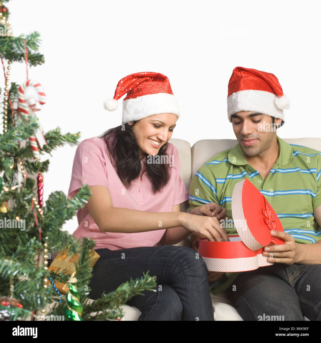 Couple sitting on a couch and unpacking a Christmas present Stock Photo ...