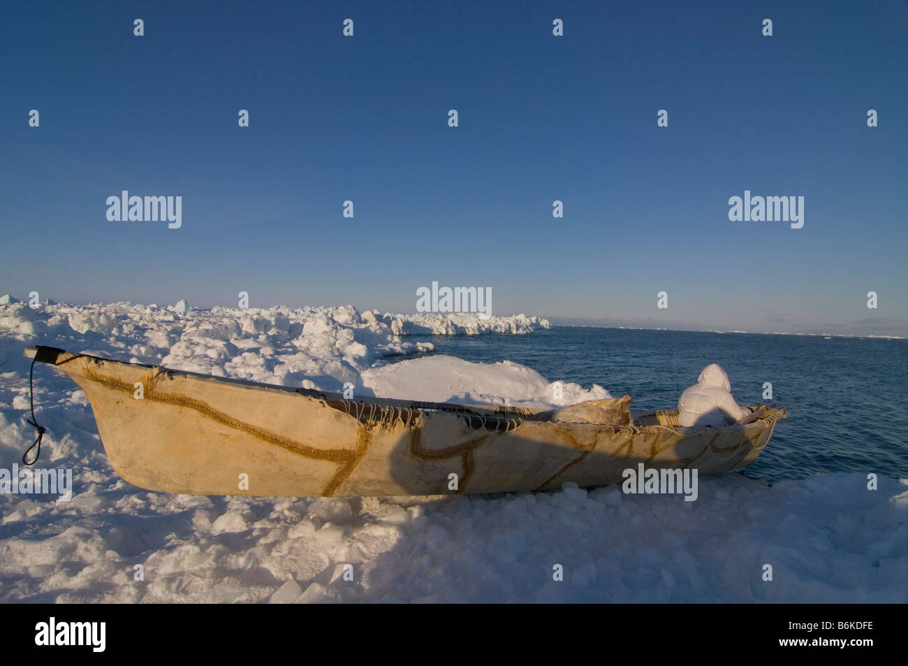 Inupiaq whaler sits in a seal skin boat or umiak waits and watches for ...