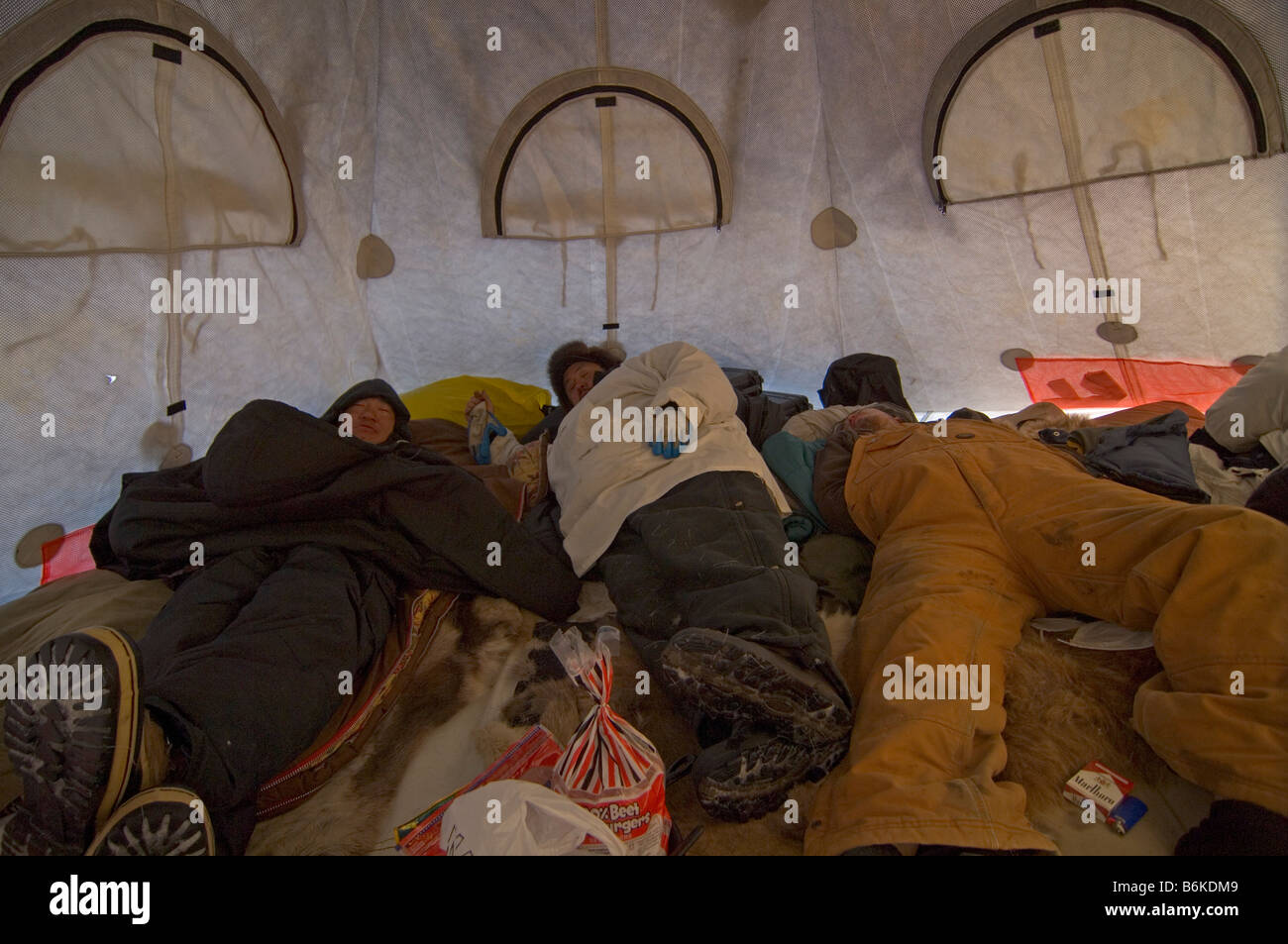 Inupiaq whalers rest on caribou skins in a tent on the pack ice during ...