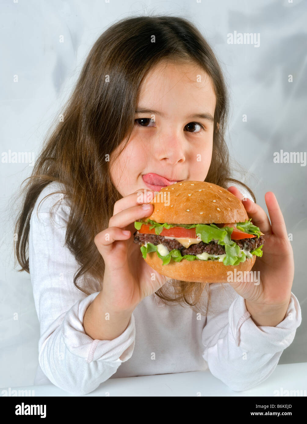 young girl eating hamburger happily Stock Photo - Alamy