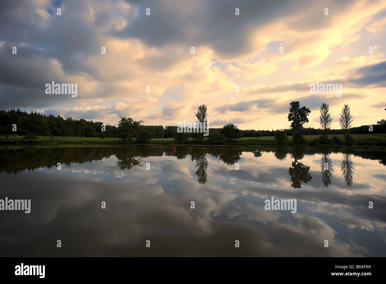 cumulo nimbus clouds at sunset reflected in a lake Stock Photo - Alamy