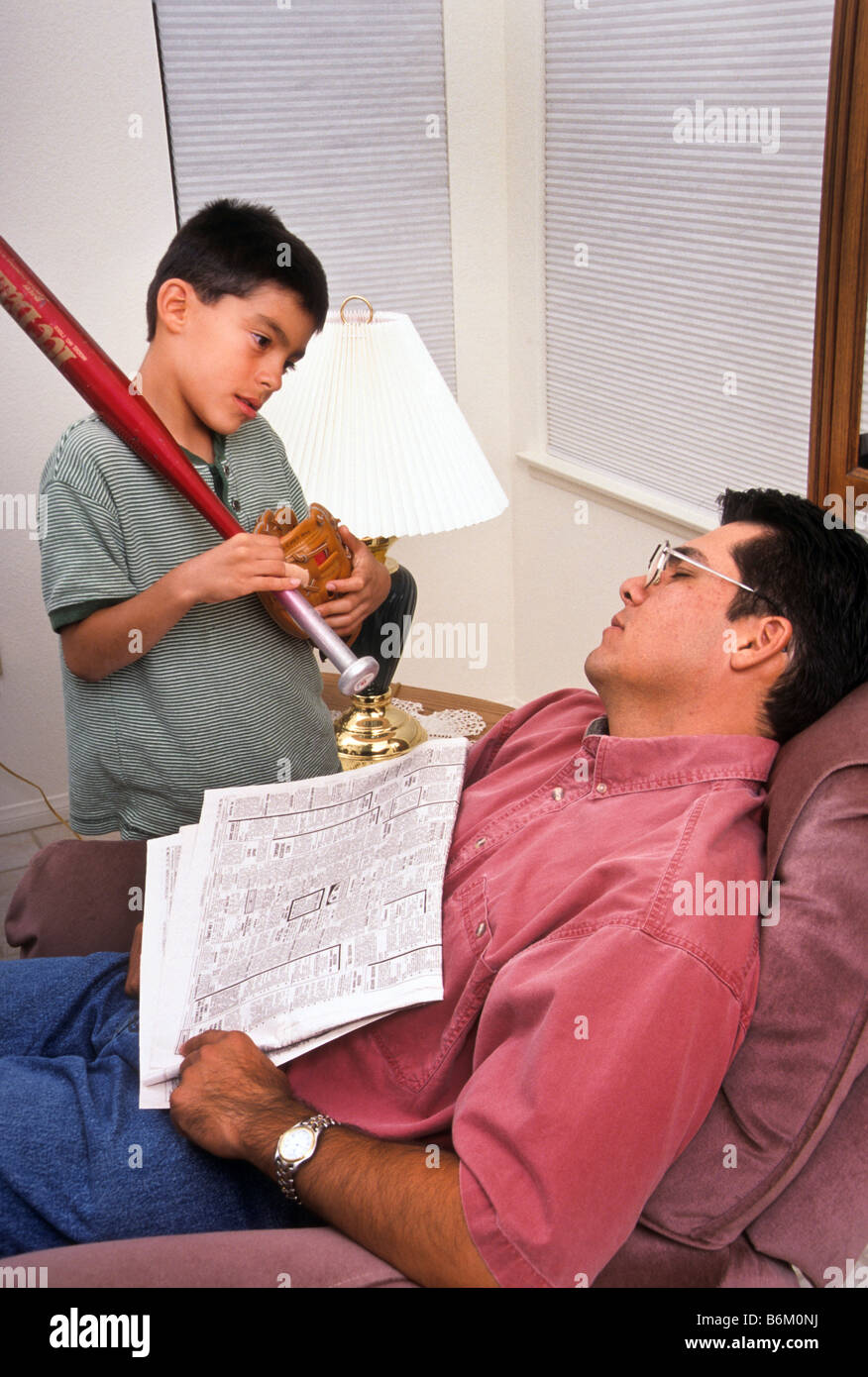 Young Hispanic boy tries to wake his napping father to play baseball ...