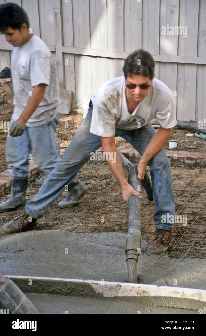 Man directs flow of concrete from hose of concrete pump to create ...