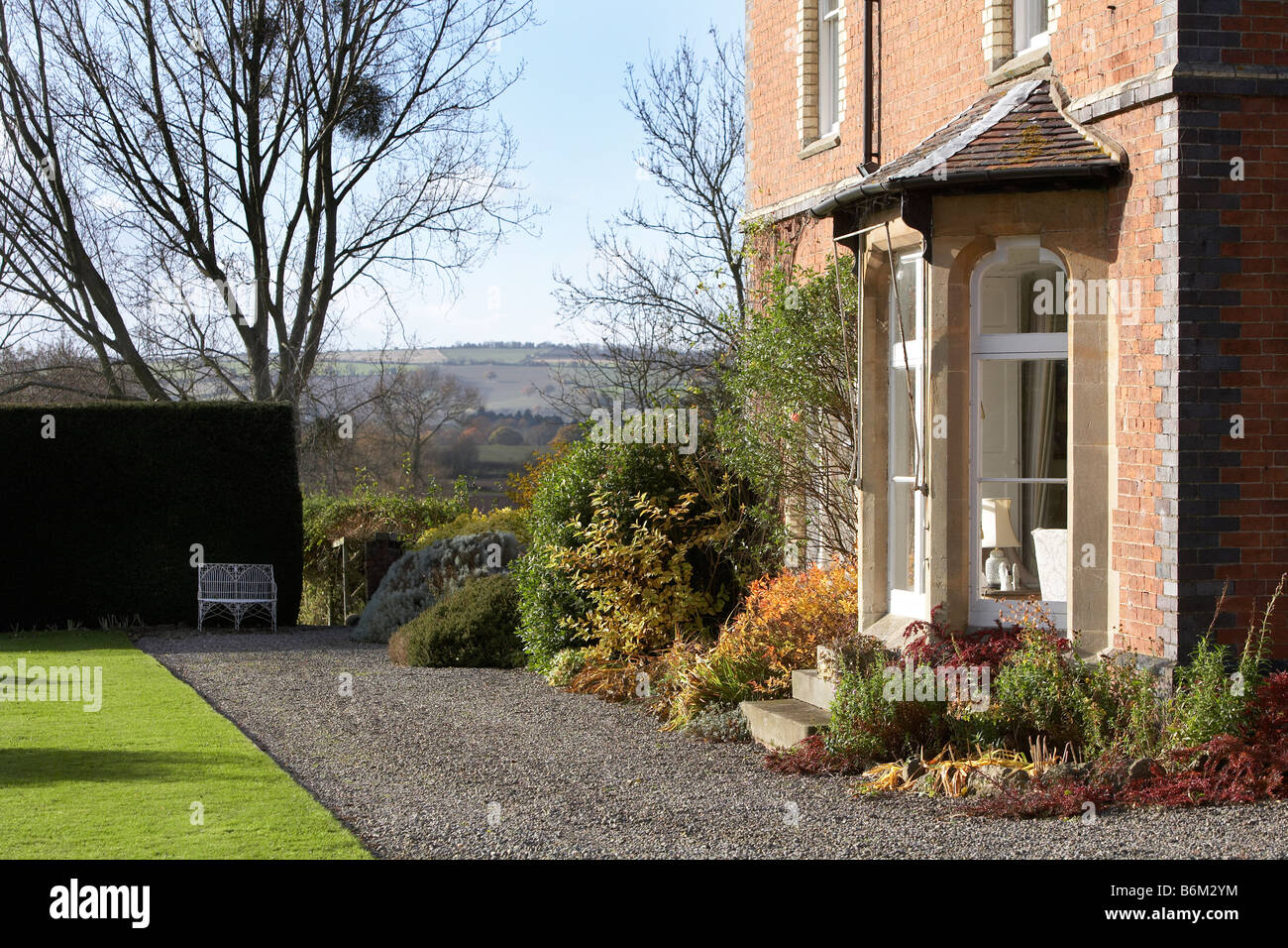 Victorian red brick bay window and view of winter garden to white bench ...