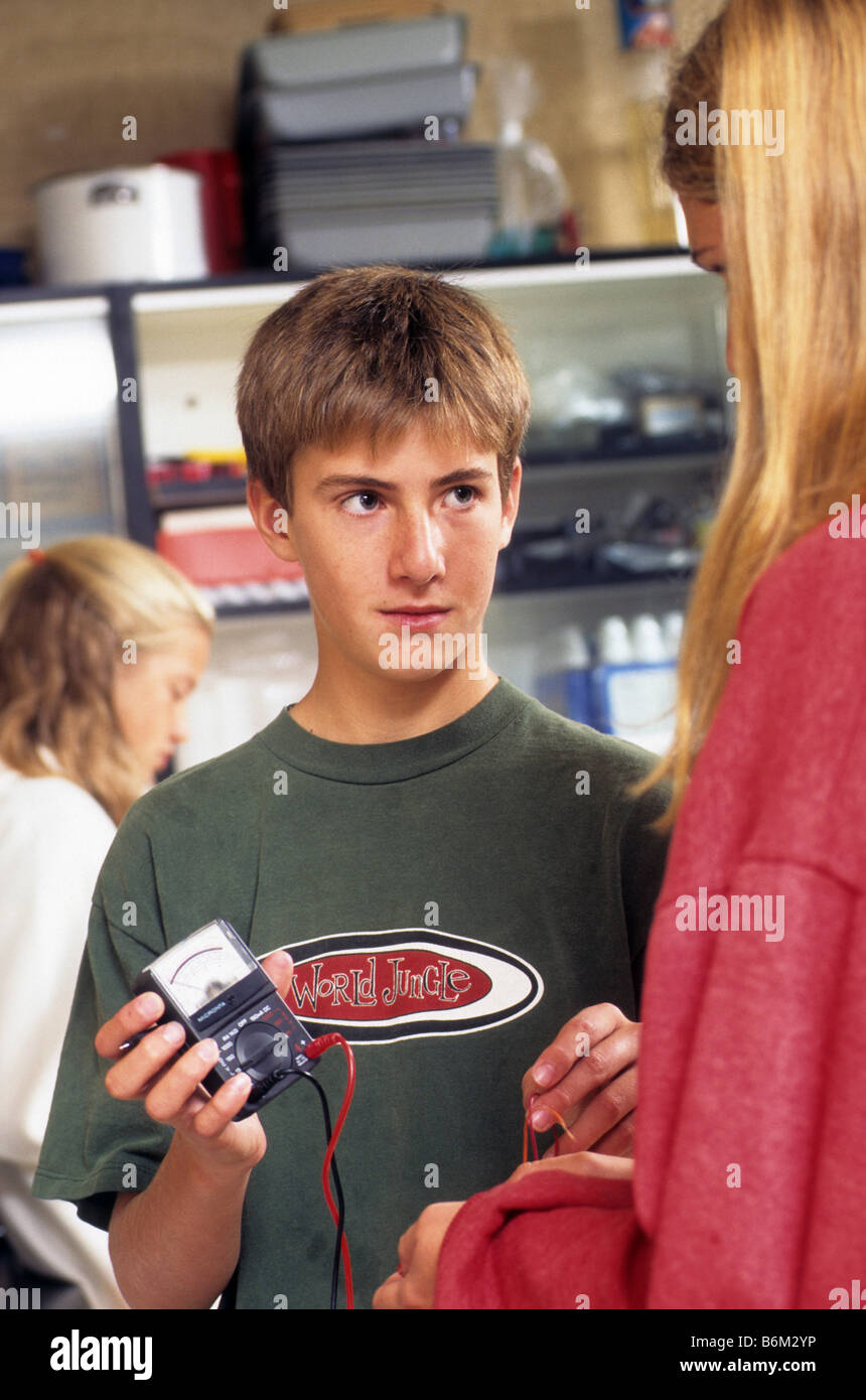 Teen boy reads meter during science experiment in school physics lab ...