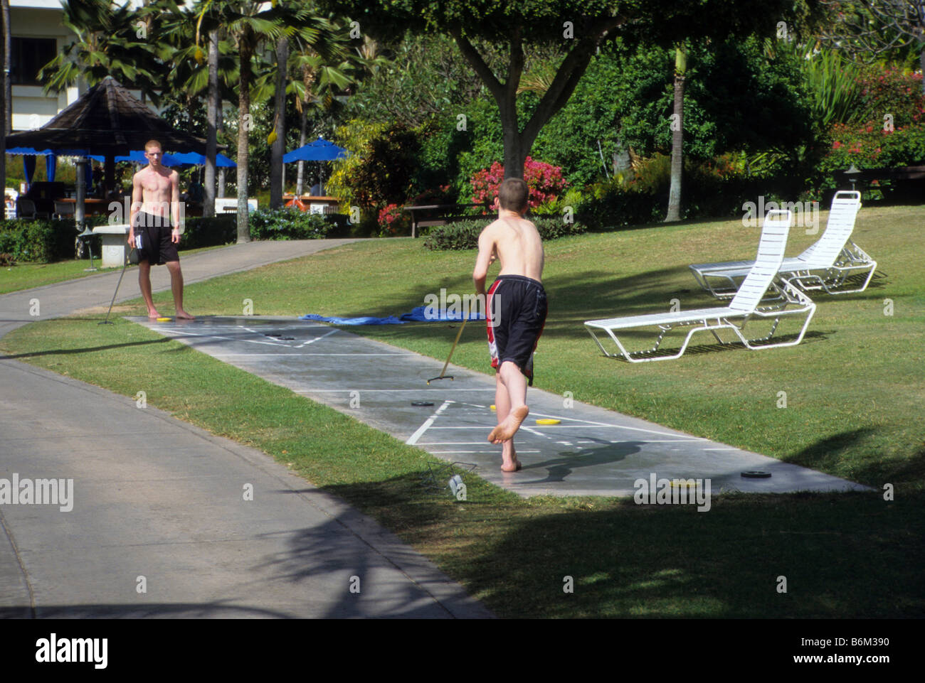 Teen boys play shuffleboard at hotel on Maui, Hawaii Stock Photo - Alamy