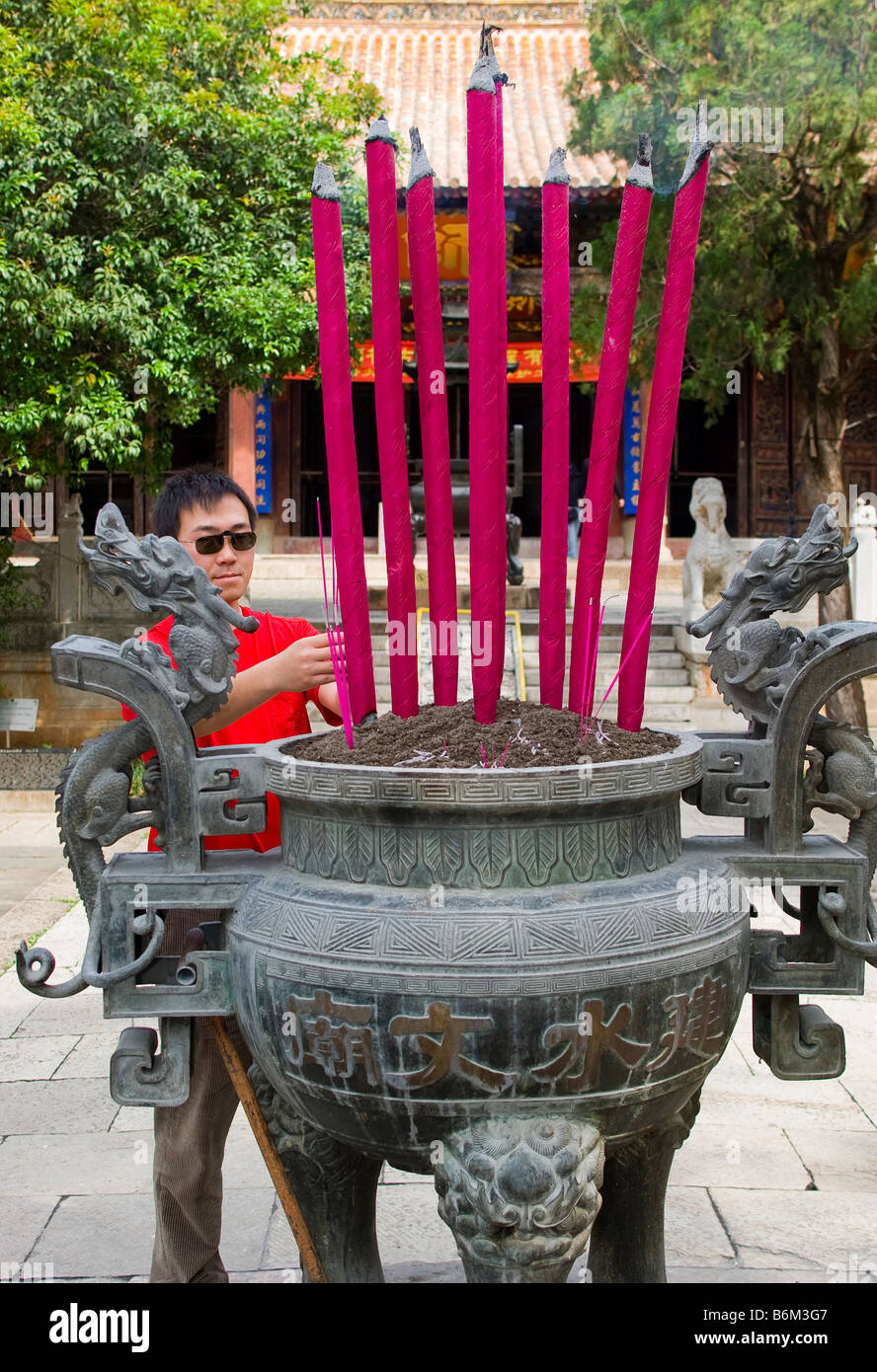 Man places incense in urn at Confucius Temple in Jianshui Stock Photo ...
