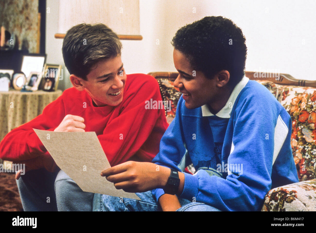 Black teen boy and white friend read a letter together Stock Photo - Alamy